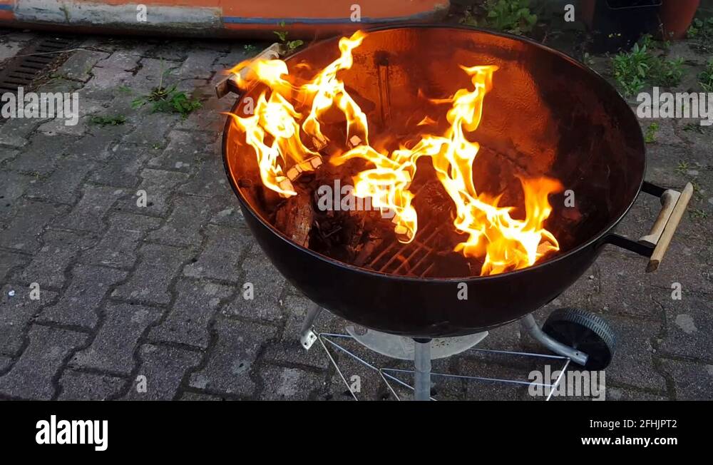 Grill lit with flames dancing high and hot. Black grill on fire with ...
