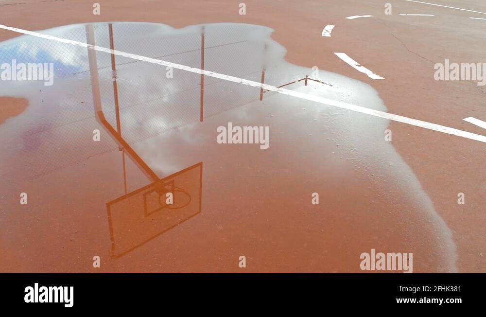 Reflection of a basketball hoop on a puddle on the basketball court ...