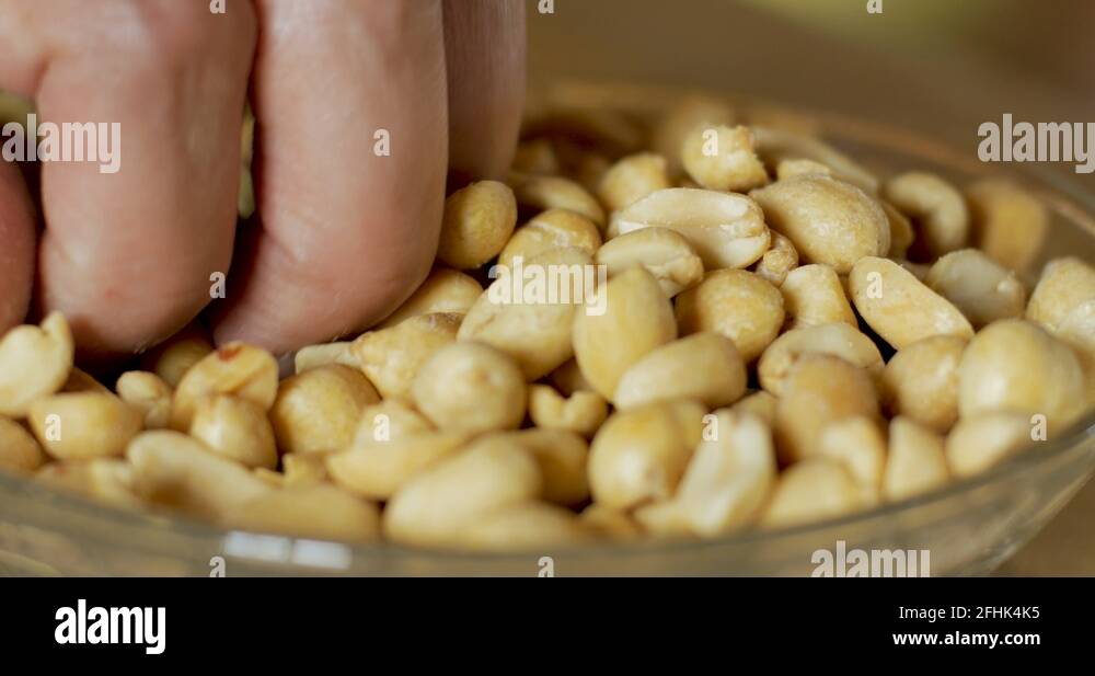 Two hands fighting each other over a bowl of salted, roasted, peanuts ...