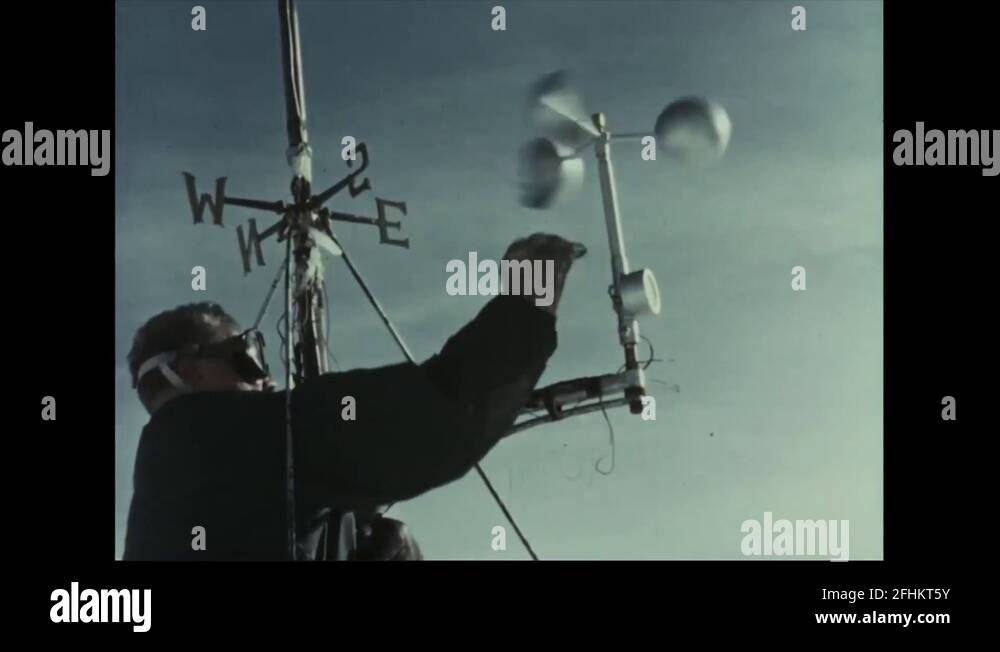 Snow ranger placing alert sign board and anemometer at mountain slope ...