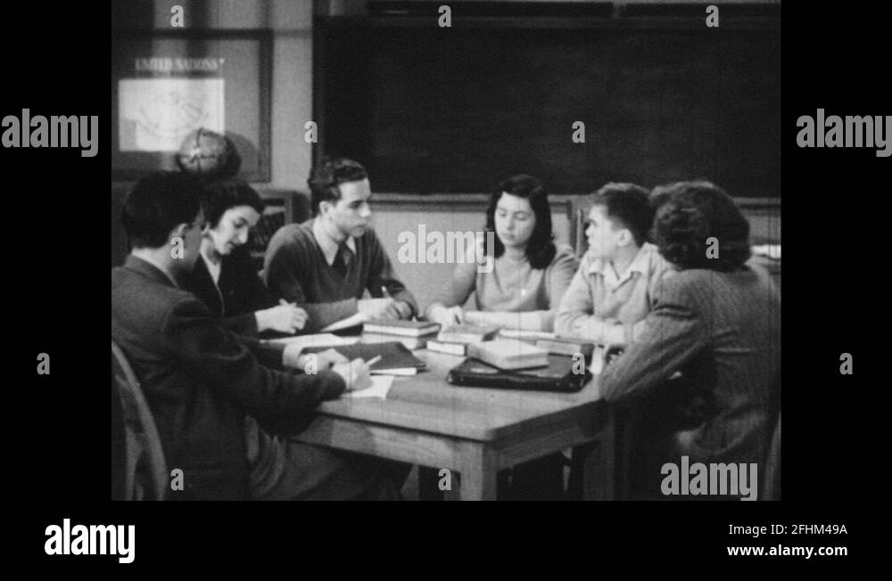 1940s: Classroom. Students sit in group and talk. Teacher approaches ...
