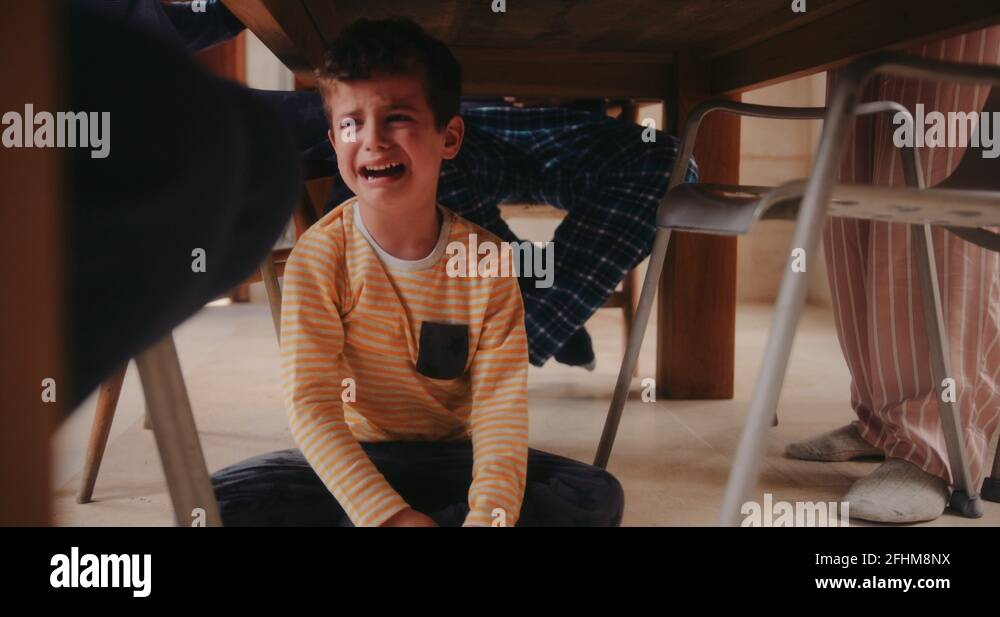 Sad crying boy sitting under kitchen table during breakfast Stock Video ...