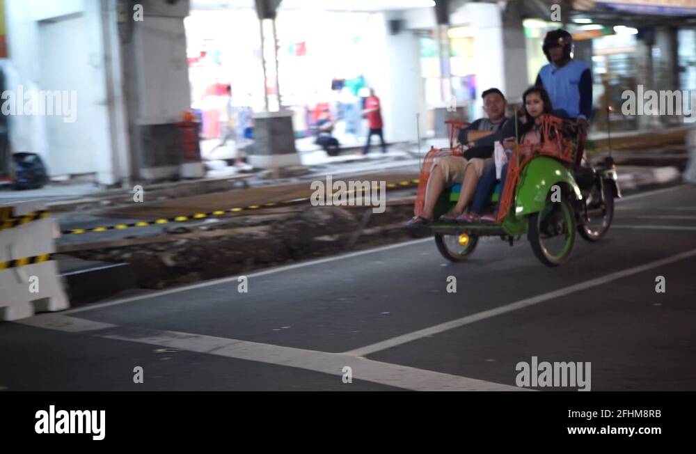 Motorized rickshaw with driver and passengers passing by in Malioboro ...
