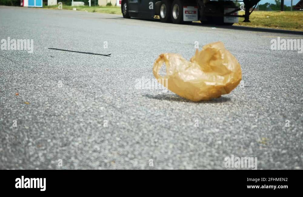 Plastic bag blowing in wind across parking lot Stock Video Footage - Alamy