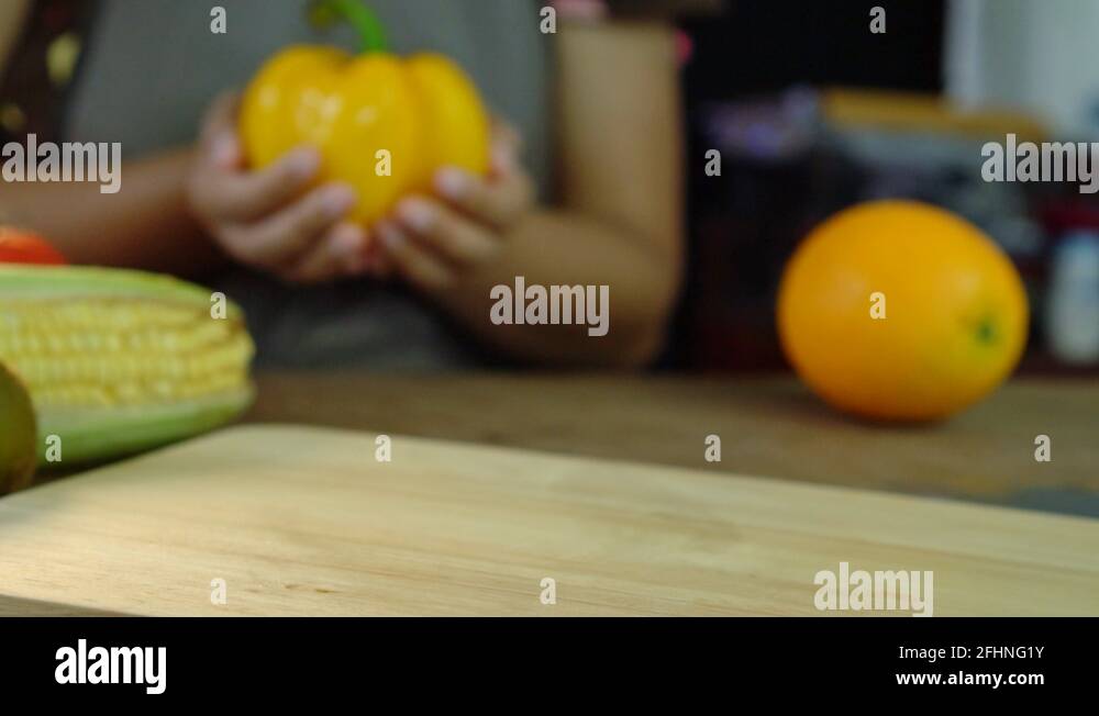 Asian female showing clean bright bell pepper on her palm in kitchen ...