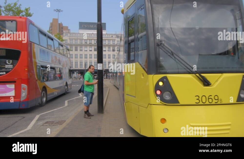Metrolink tram pulls to a stop beside buses by Piccadilly Gardens ...