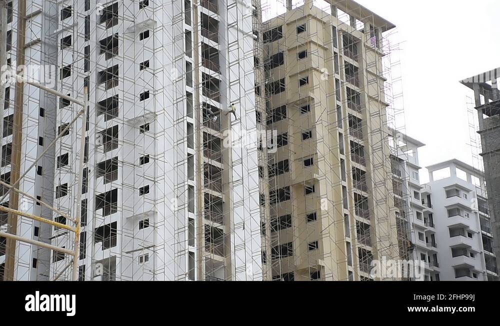 Two construction workers working on a tall building without much ...