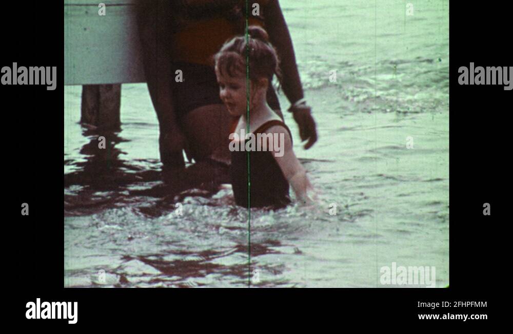 1970s: Girl splashes and wades in shallow pool. Children splash and ...