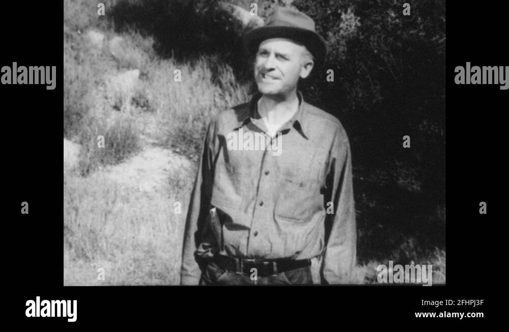 1950s: Scrubby, wild landscape, man talks, smiles, gestures. Men talk ...