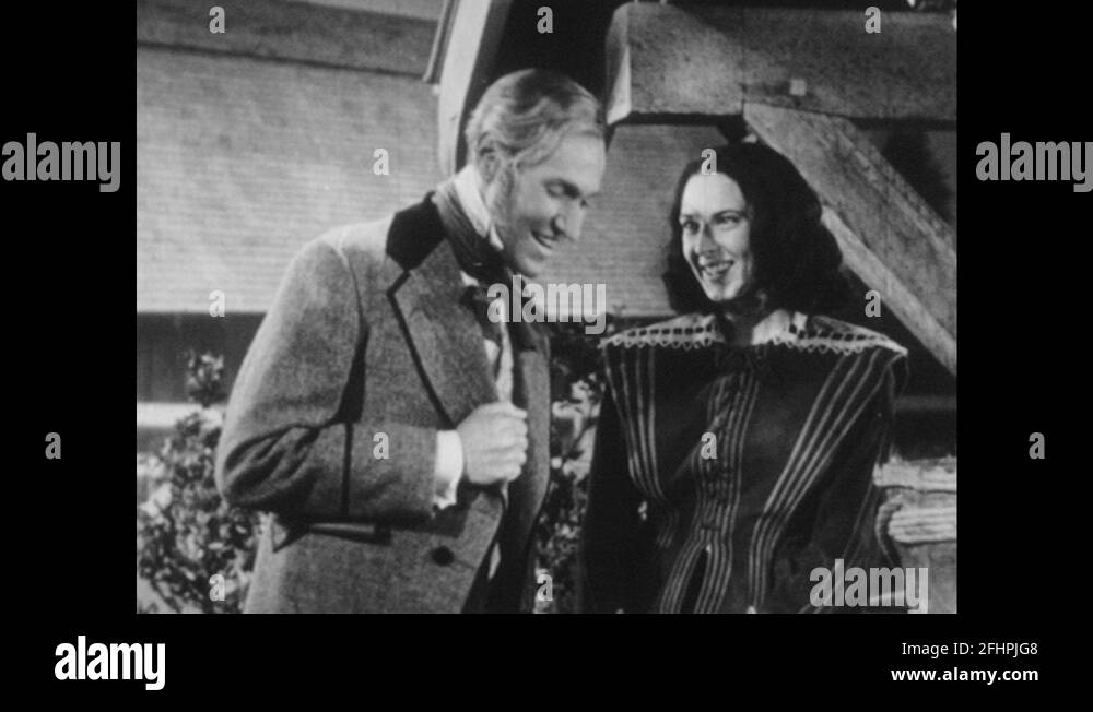 1950s: UNITED STATES: lady talks to man on bench in barn. Lady in ...