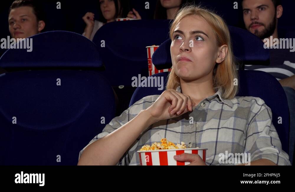 Attractive female eating popcorn at movie premiere at the cinema Stock ...