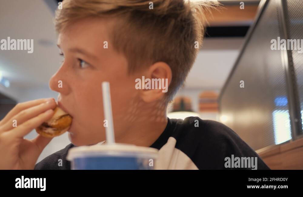 A boy in a fast food cafe. Eating burgers and french fries in fast food ...