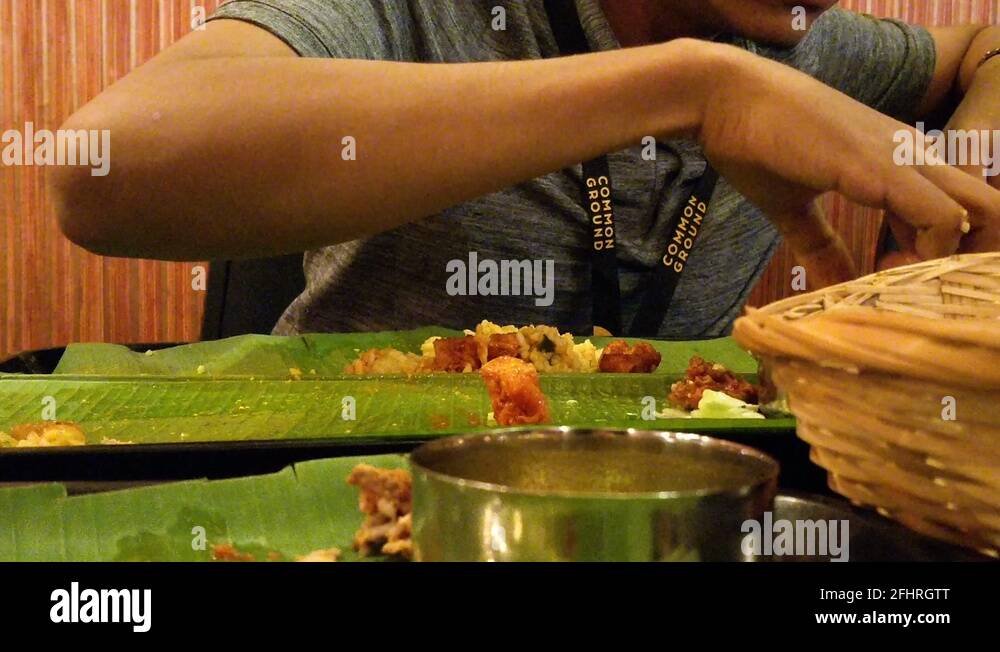 A man eats traditional Indian food with his fingers. Food is served on ...