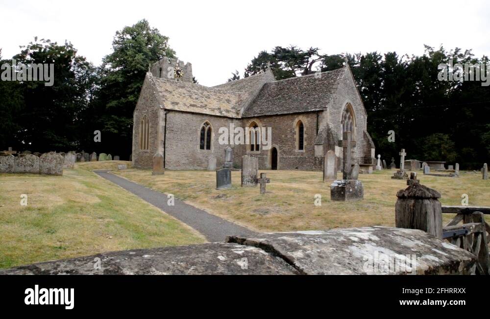 English country churchyard seen over stone wall and wooden entrance ...