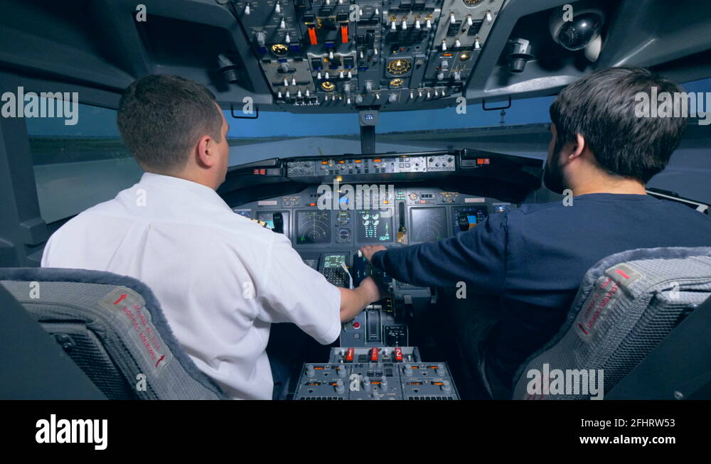 Two men are sitting in a cockpit of a flight simulator. Cockpit cabin ...