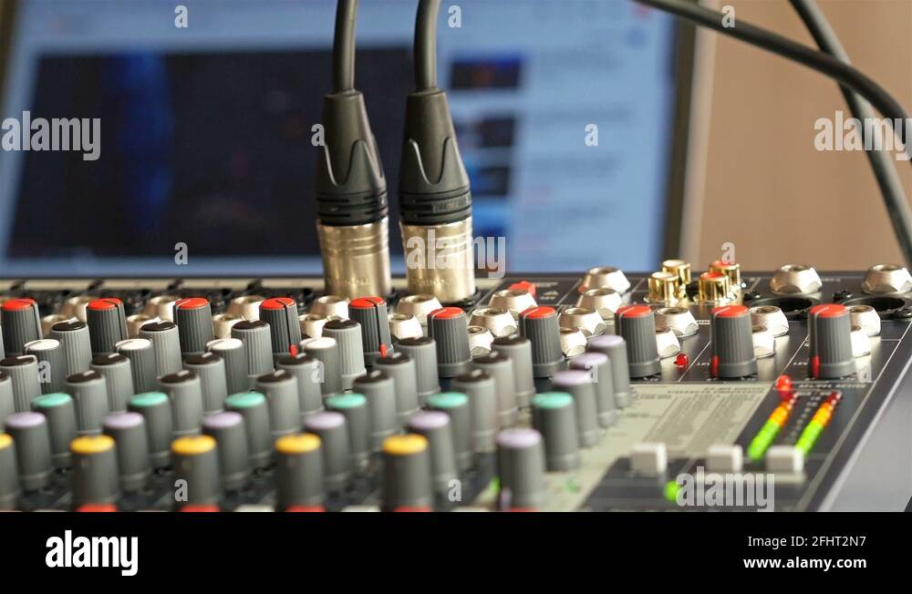 Man adjusting audio mixer in studio with computer screen at background ...