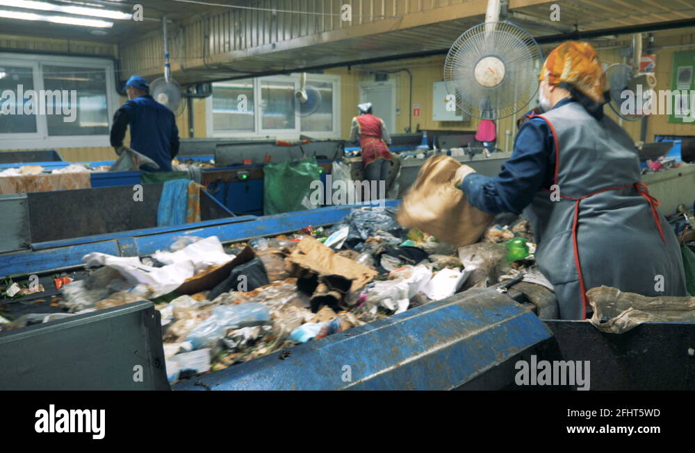 Garbage moves on conveyors, while workers sorting it at a recycling ...