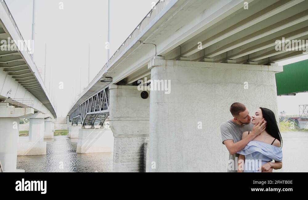 A loving couple are standing under a bridge hugging and kissing Stock ...