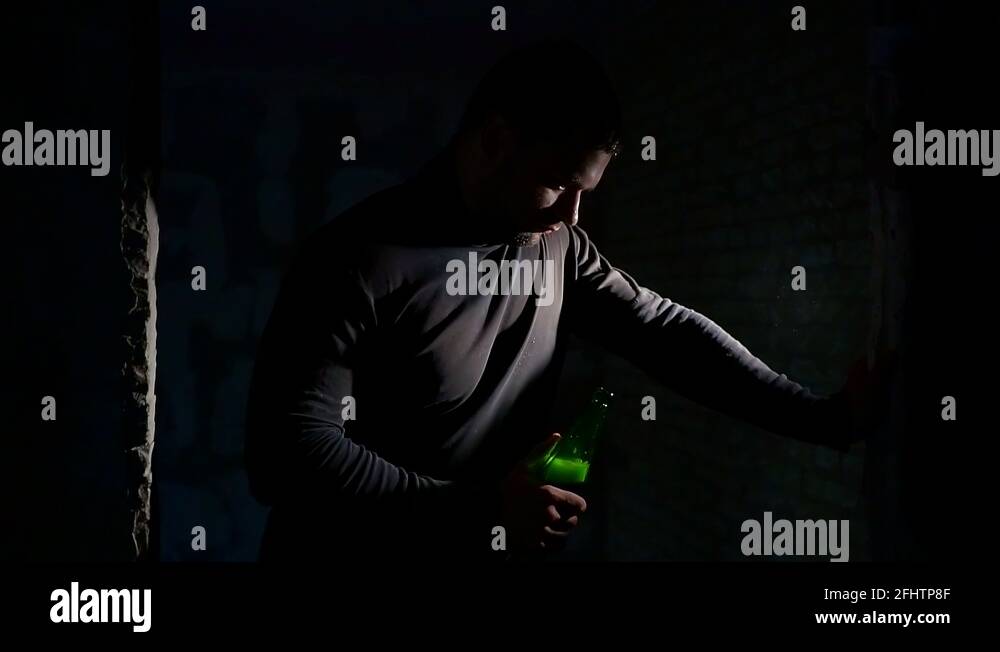 drunk alcoholic man standing in a ruined building in the dark and ...