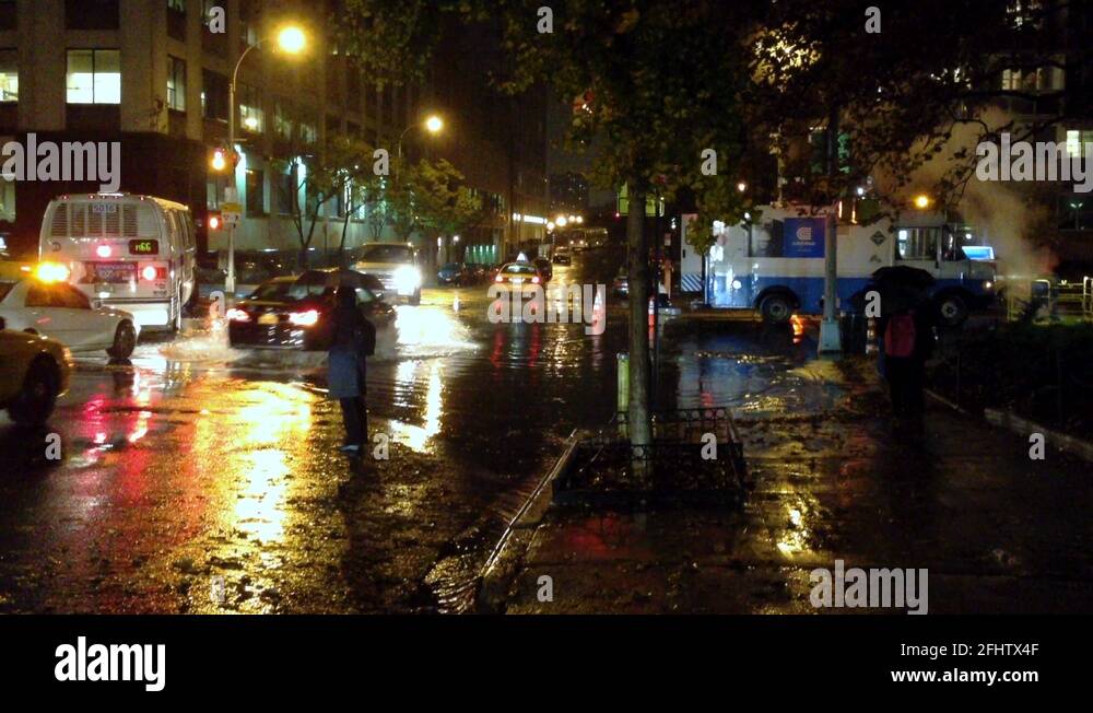 Massive puddle floods a busy city intersection as workers and people ...