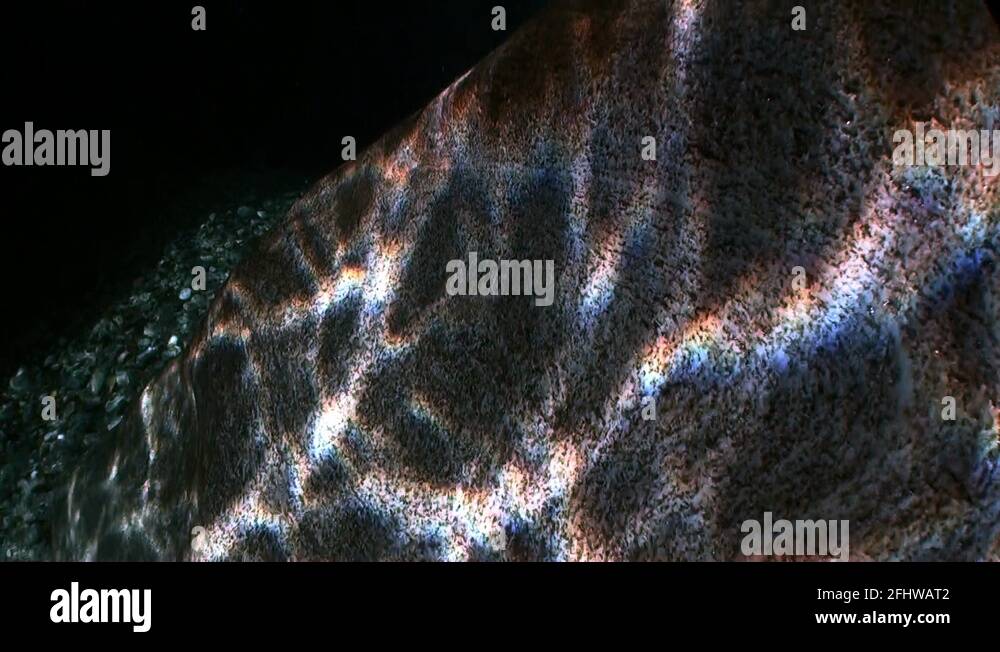 Refraction of sunlight underwater on smooth stones of river Verzasca ...