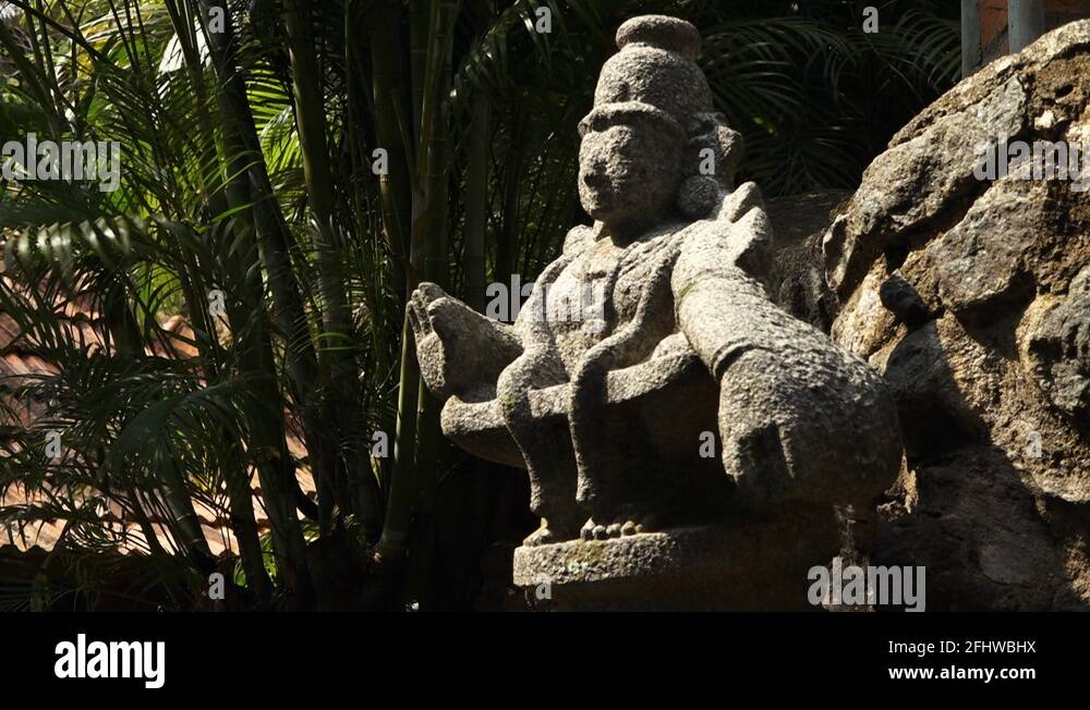 A historic carved stone statue of a person sitting on a throne with big ...
