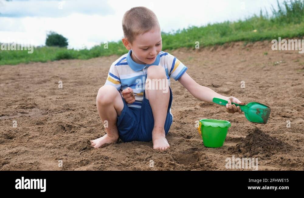 Little boy is playing digging a pit with a shovel. Kid playing on the ...
