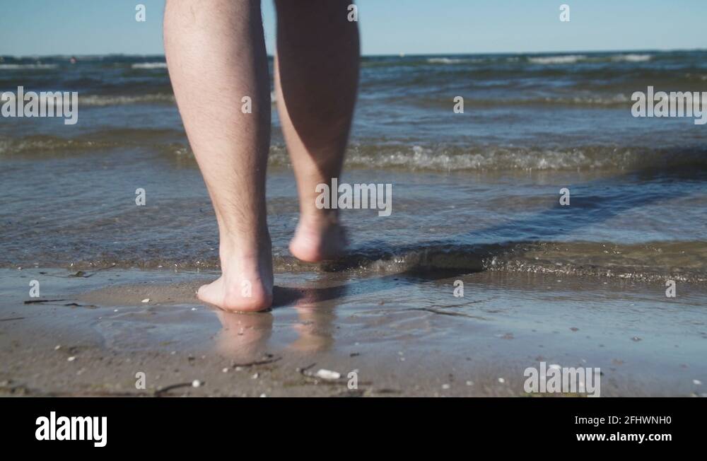 Low angle of man walking into the ripple edge of the sea 4K Stock Video ...