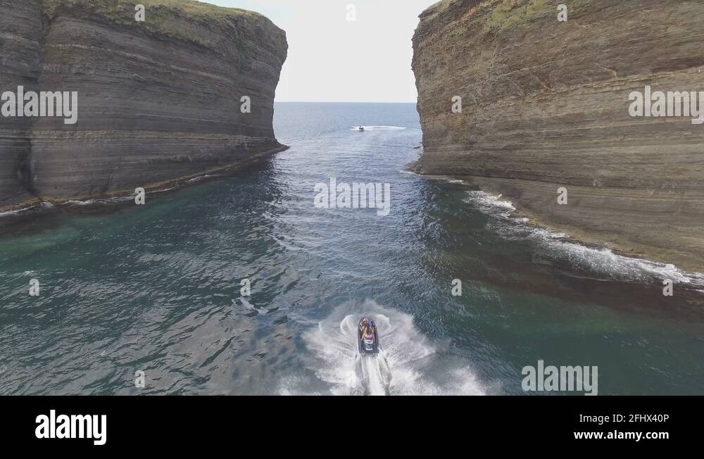 Personal watercraft and a boat pass through a narrow cliff-lined ...