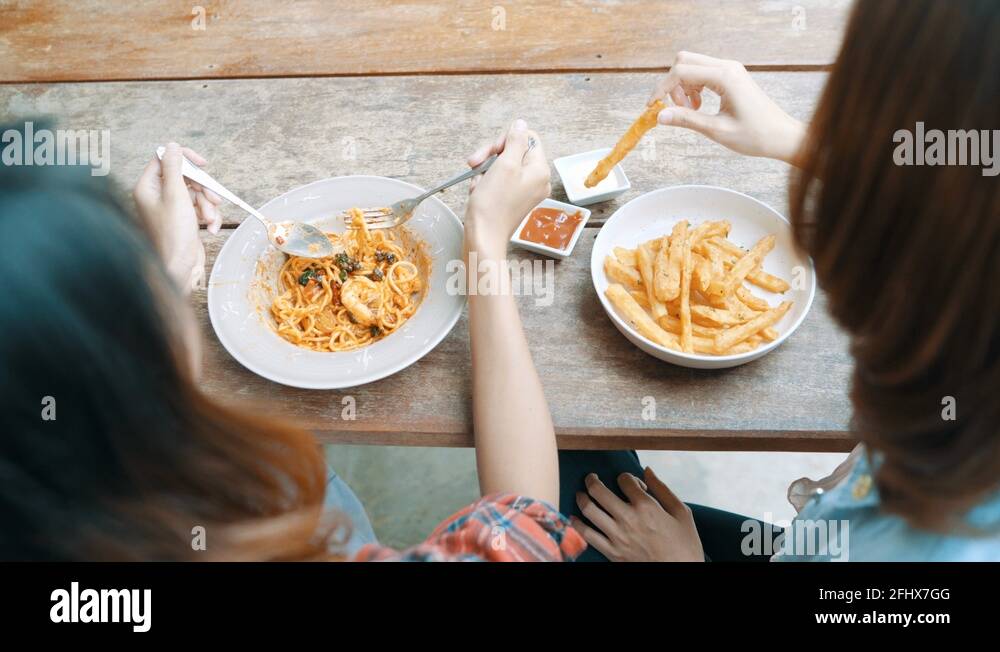 Beautiful happy Asian women lesbian couple sitting each side eating ...