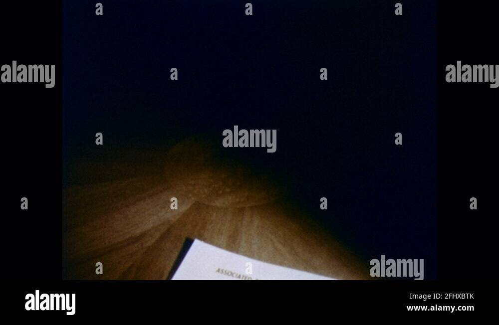 1960s: Ray of light on a certificate with gold seal. Hands pick up ...