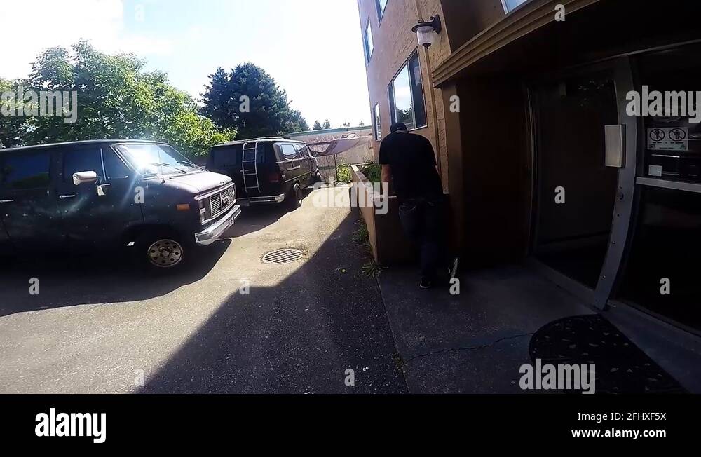 Man stands outside a residential building by the door with his back ...