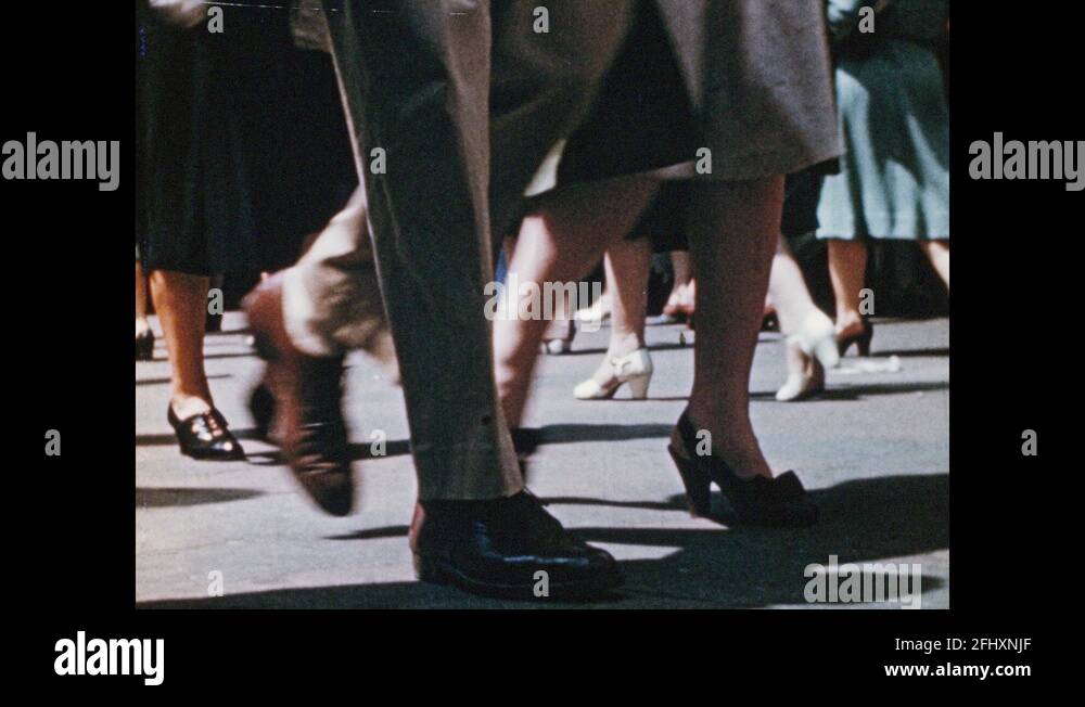 1950s: People shown from the legs down walk on sidewalks. Man measures ...