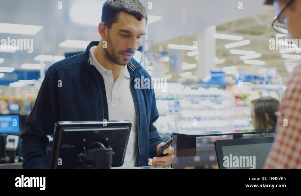 At the Supermarket: Checkout Counter Customer Pays with Smartphone for ...