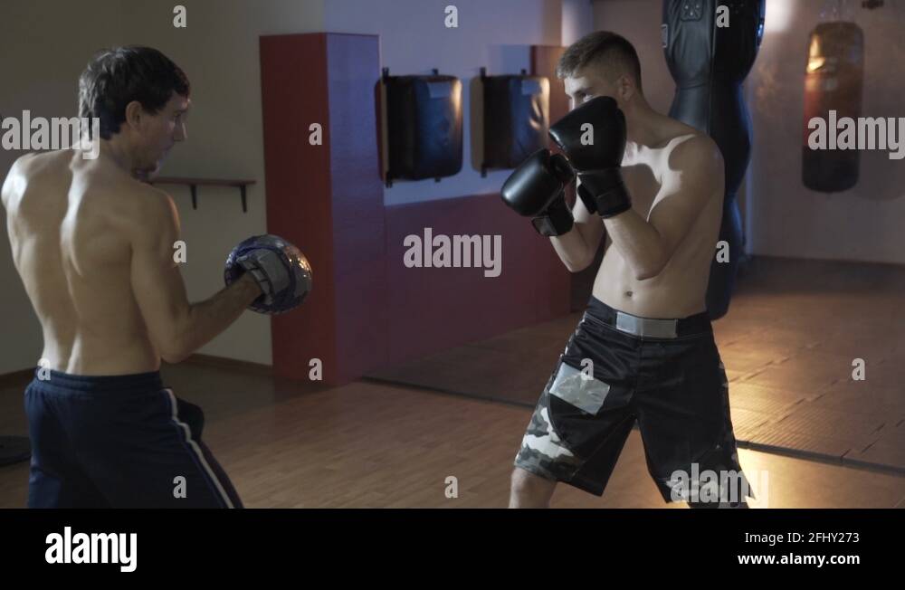 Slow-motion shooting coach in boxing paws is training a young boxer in ...