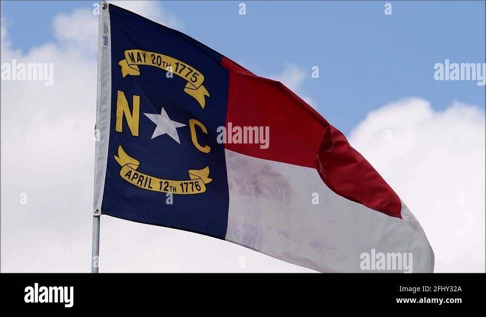 The North Carolina State flag waves in the wind against a blue sky and ...