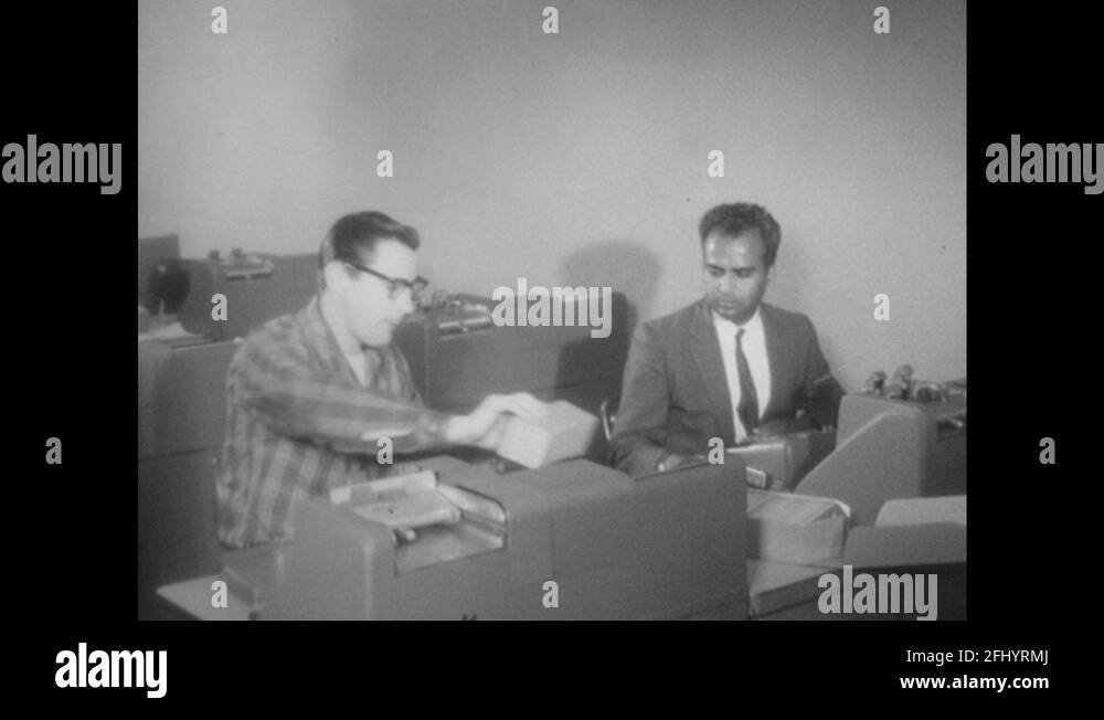 1960s: Men at keypunch machines, man gives punch cards to man. Punch ...