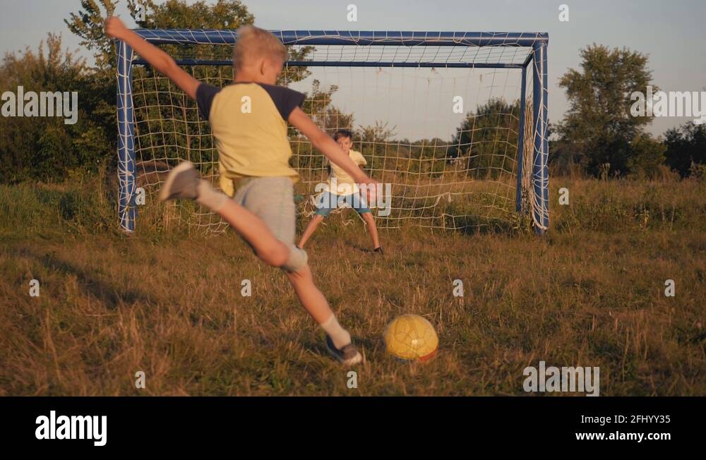 Two boys playing soccer at sunset. A soccer ball is hitting. Football ...