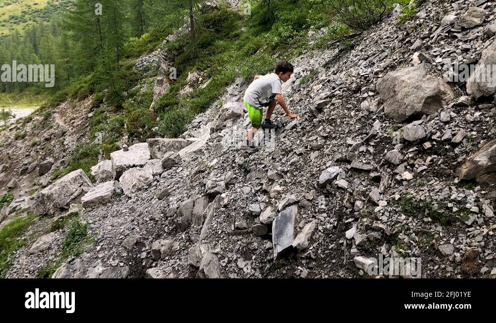 Cute young boy doing well while climbing mountain full of rubble Stock ...