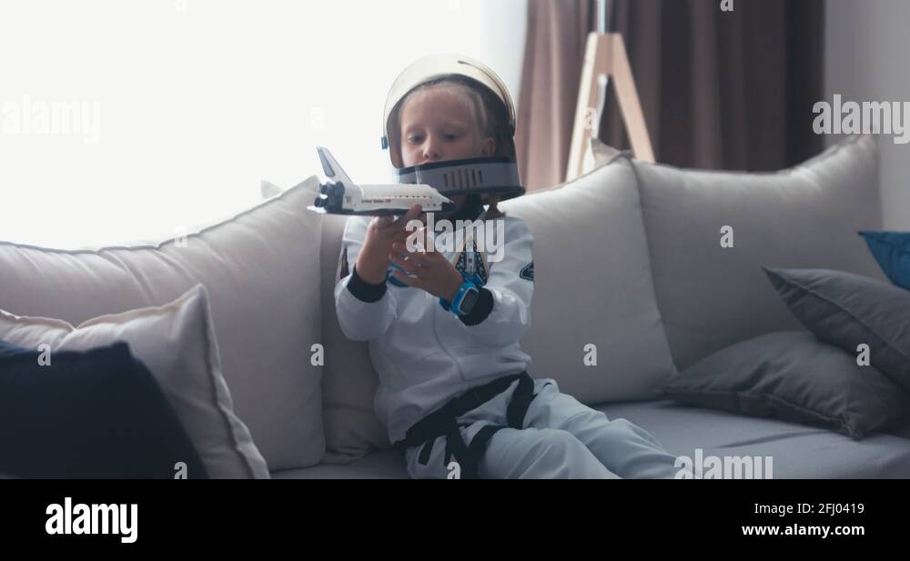 Cute little girl wearing astronaut suit playing with a toy space ...