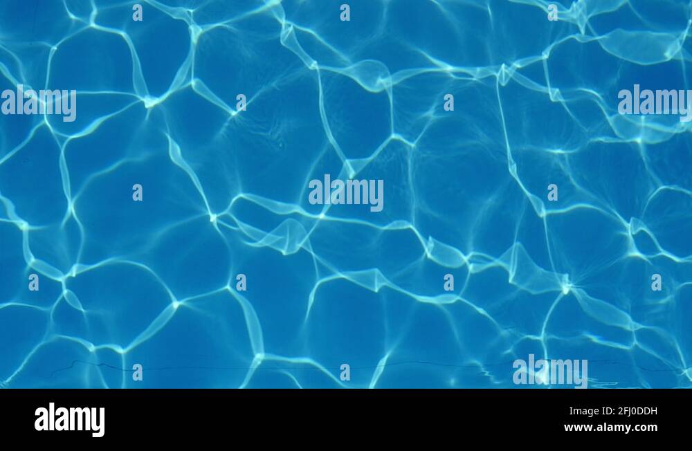 Relaxing swimming pool water shining with its swaying light blue waves ...