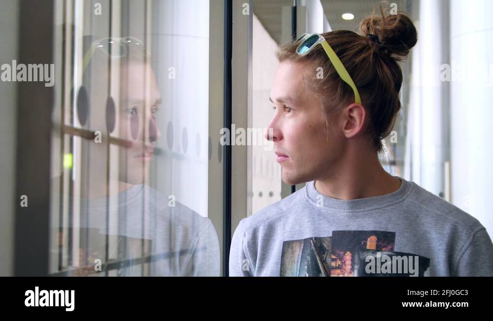 Modern man looking out window with accompanying sight. Guy watching in ...