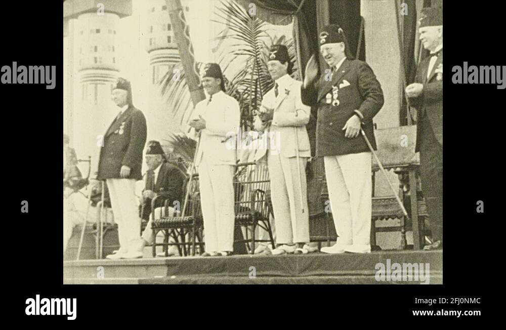 1920s: Shriners wearing hats and holding canes clap from the stage ...
