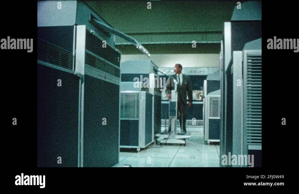 1930s: UNITED STATES: man walks through modular computer units. Man ...