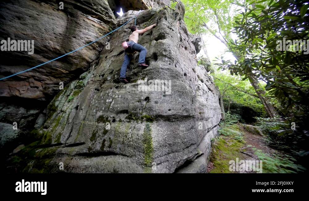 Shirtless man climbs up a roc and camera turns to reveal a woman ...