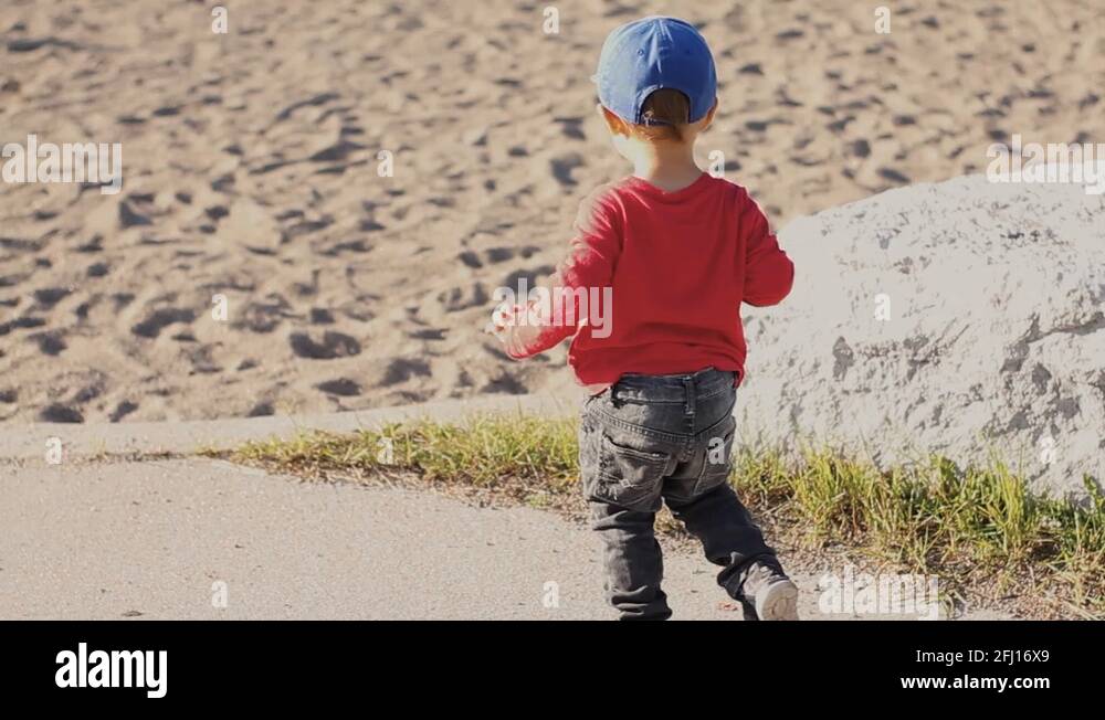 Little Boy running down a pathway in a park Stock Video Footage - Alamy