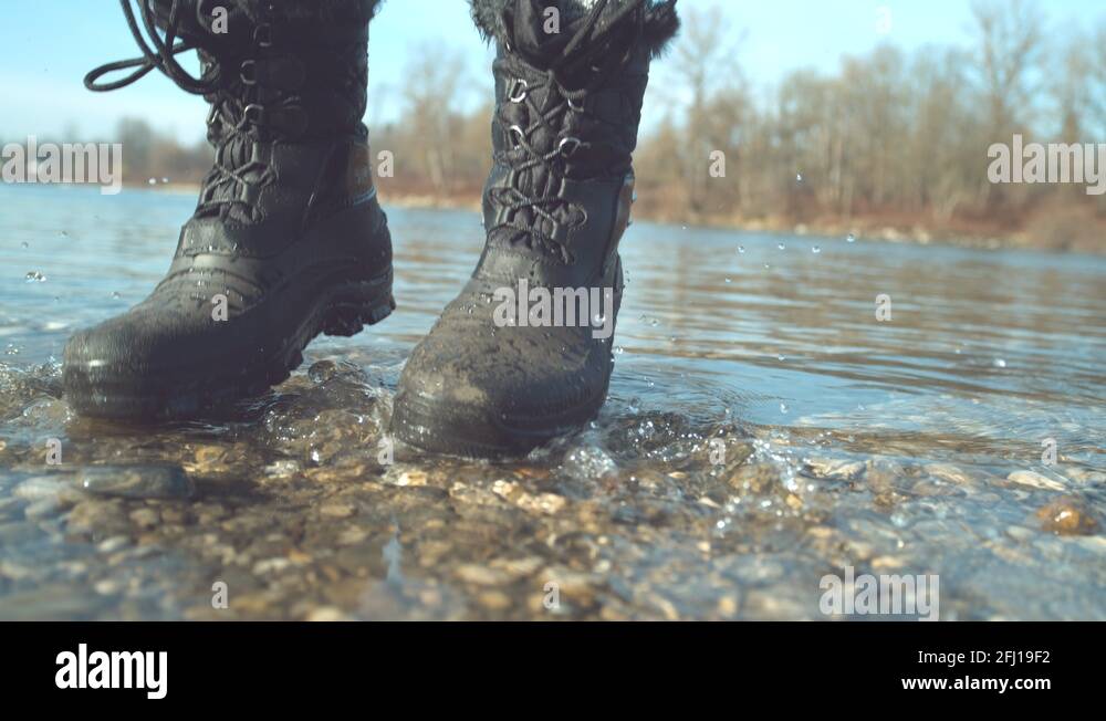 CLOSE UP Cheerful girl stomping her feet in the shallow lake and ...