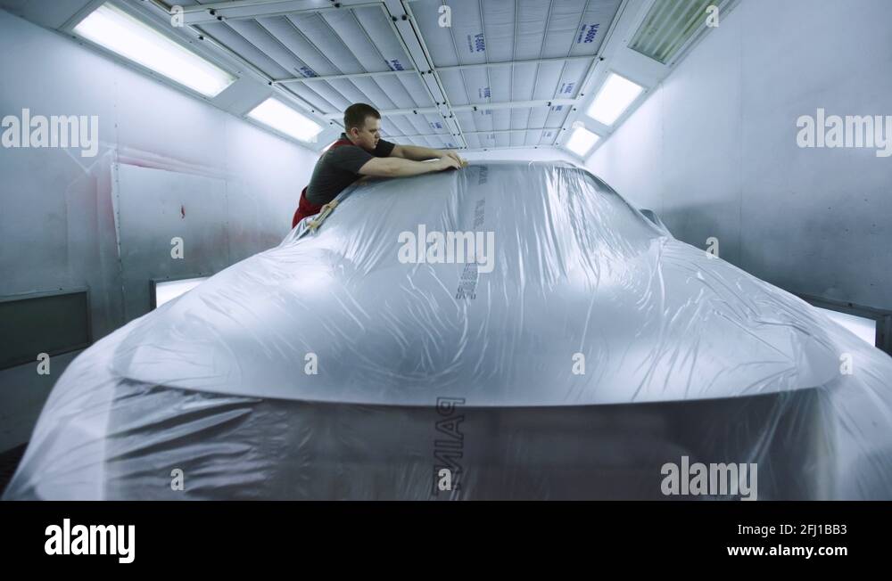 Overview of car covered by drop cloth at painting booth Stock Video ...