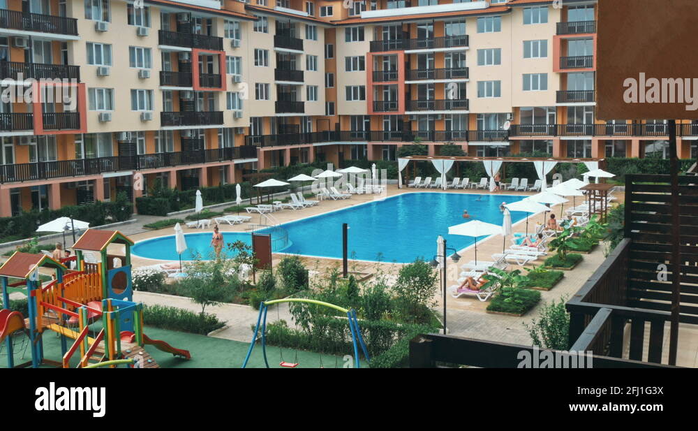 People sitting by the poolside of a resort swimming pool during summer ...