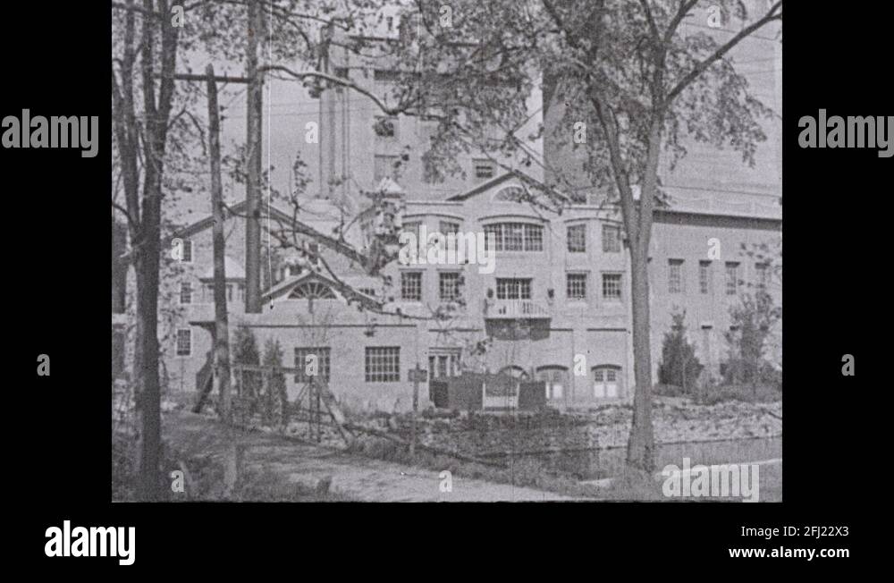 1930s: Exterior of large mill building from the front and back. Train ...